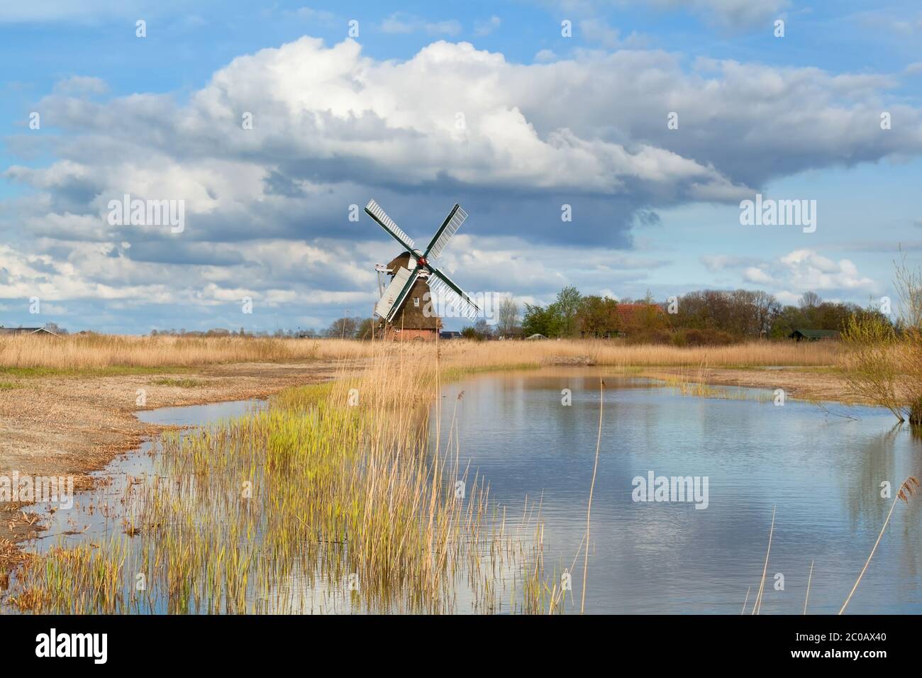 Dutch windmill over blue sky by river Stock Photo - Alamy