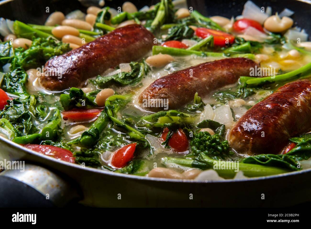 Cooking Italian spicy sausage and broccoli rabe with dramatic lighting ...