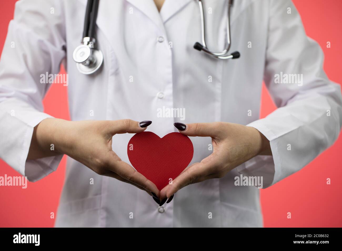 Close up view of cardboard red heart in female doctor's hands ...