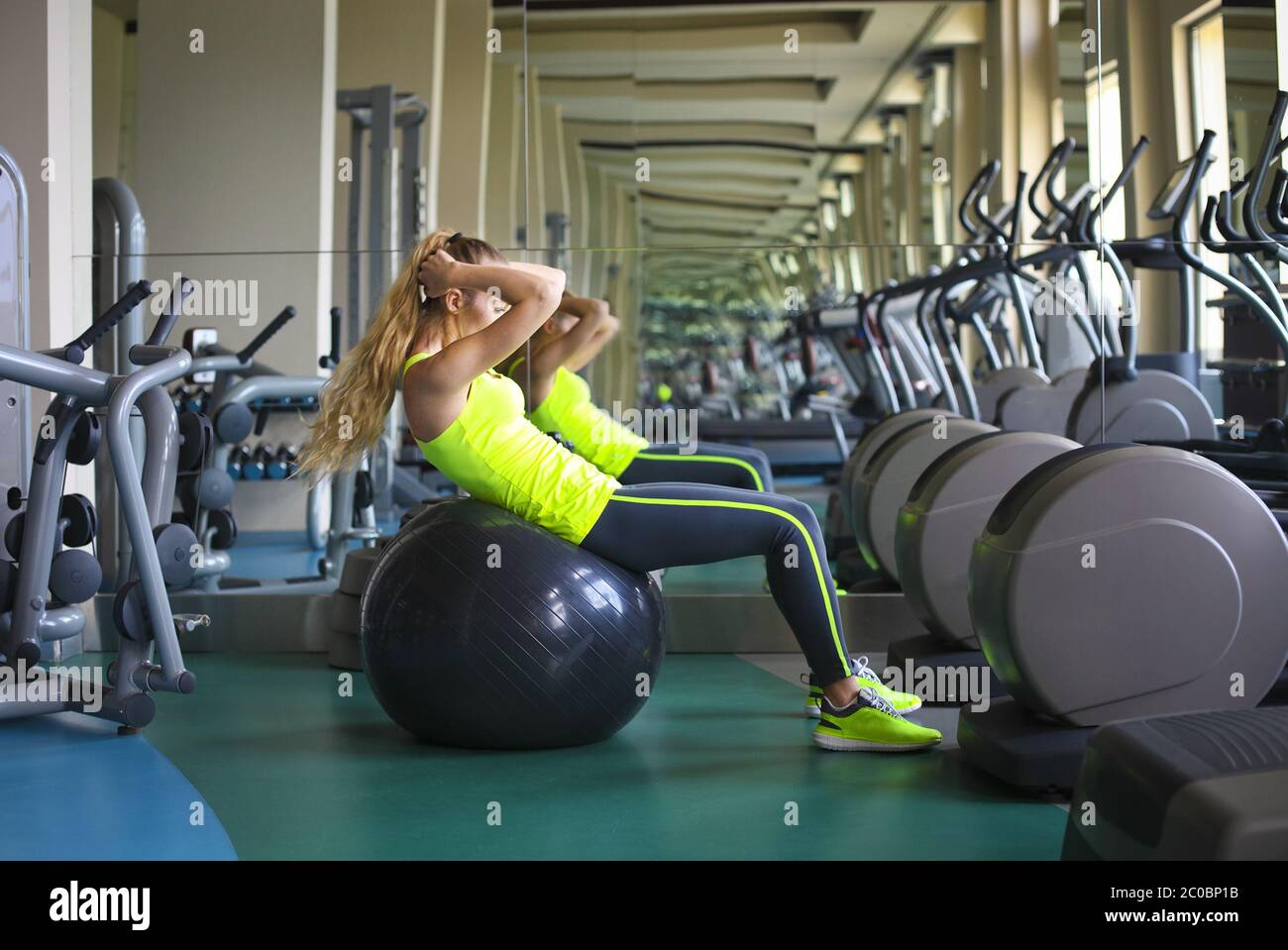 Young fit woman doing sit-ups on exercise ball in gym Stock Photo - Alamy