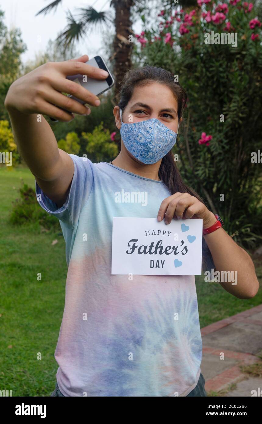 Young girl smiling at cellphone during video call to a father at home ...