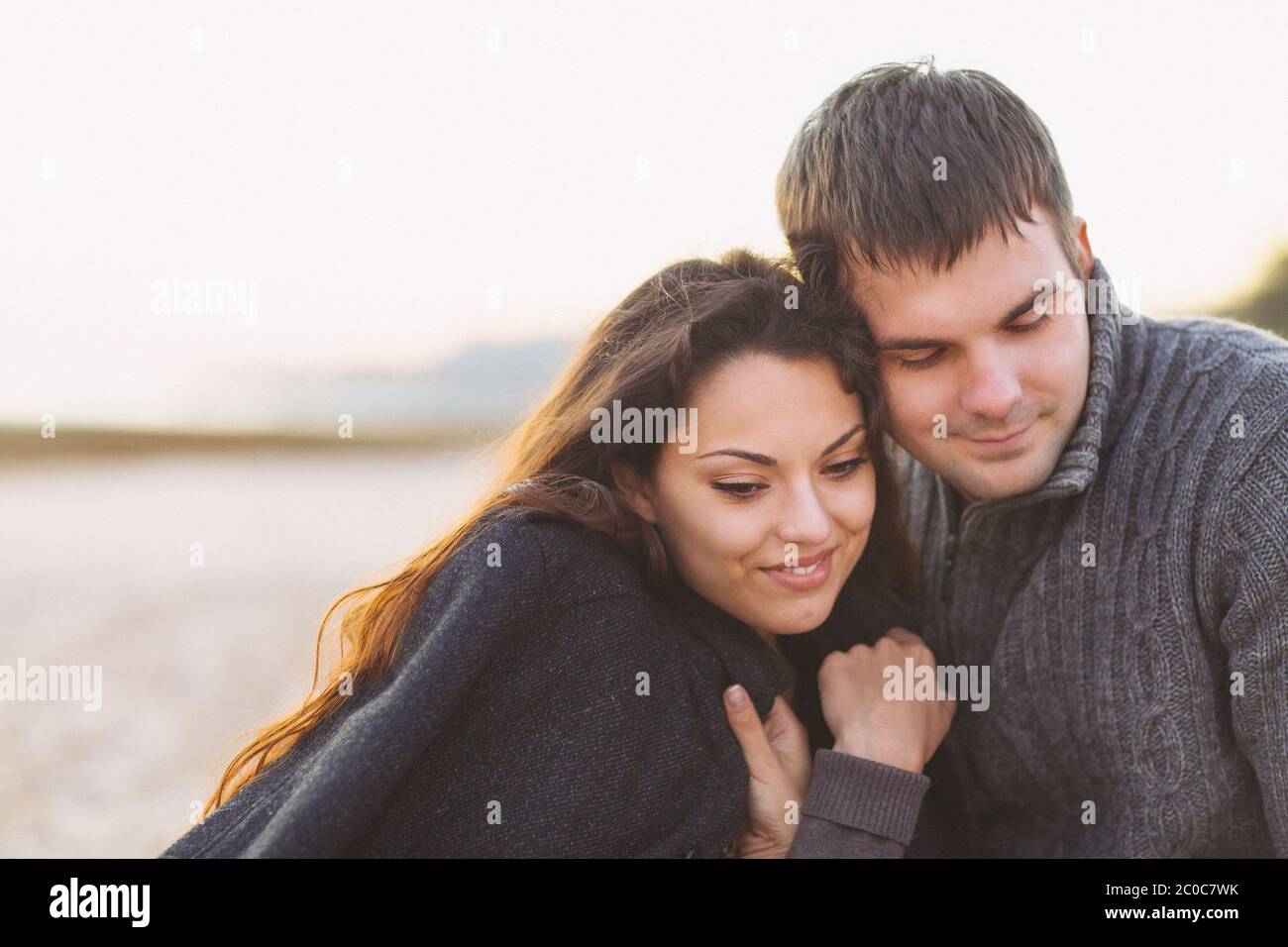 Portrait of young happy couple laughing in a cold day by the autumn sea ...
