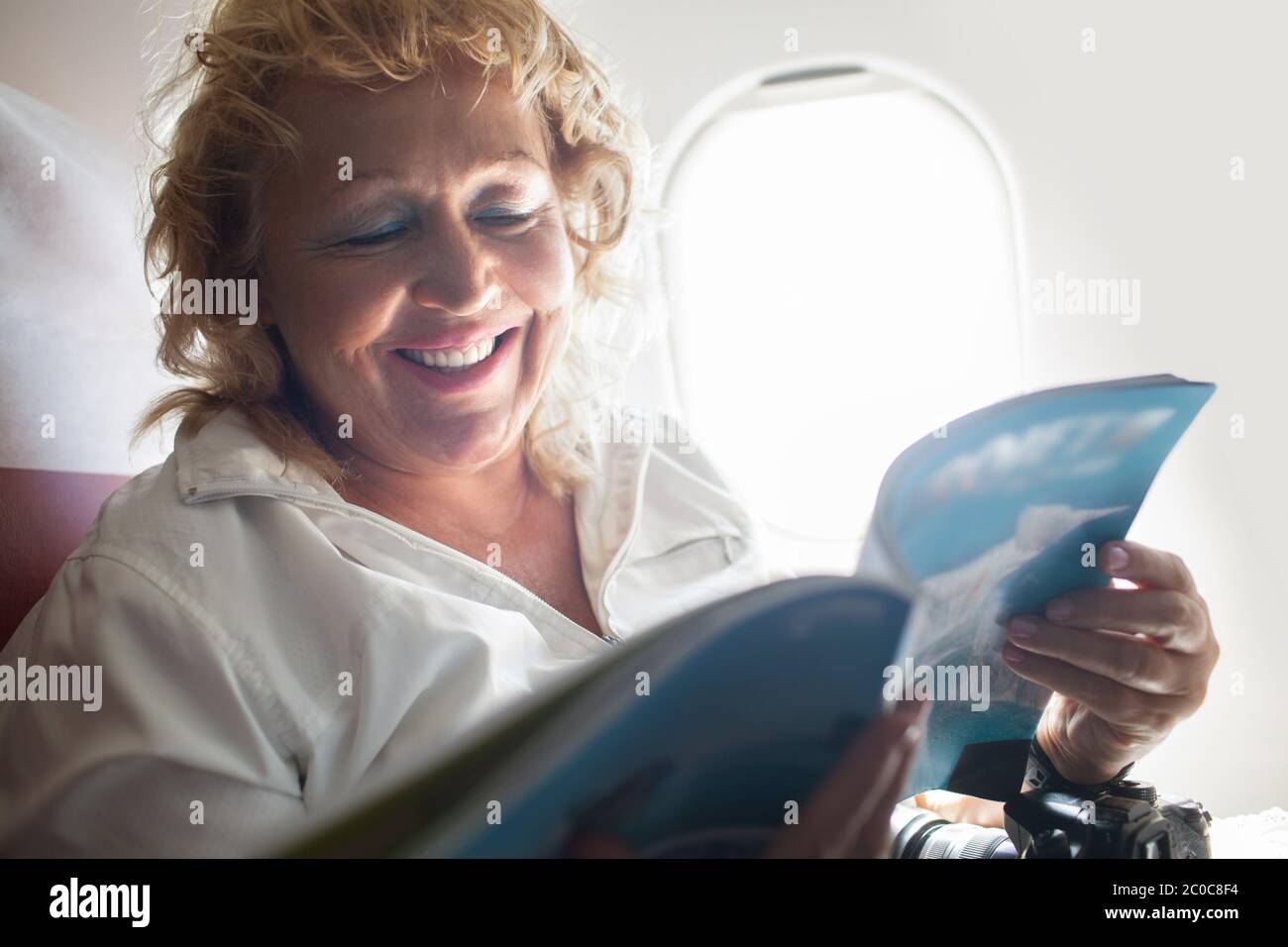 Mature Woman Reading Magazine on a Plane Stock Photo - Alamy