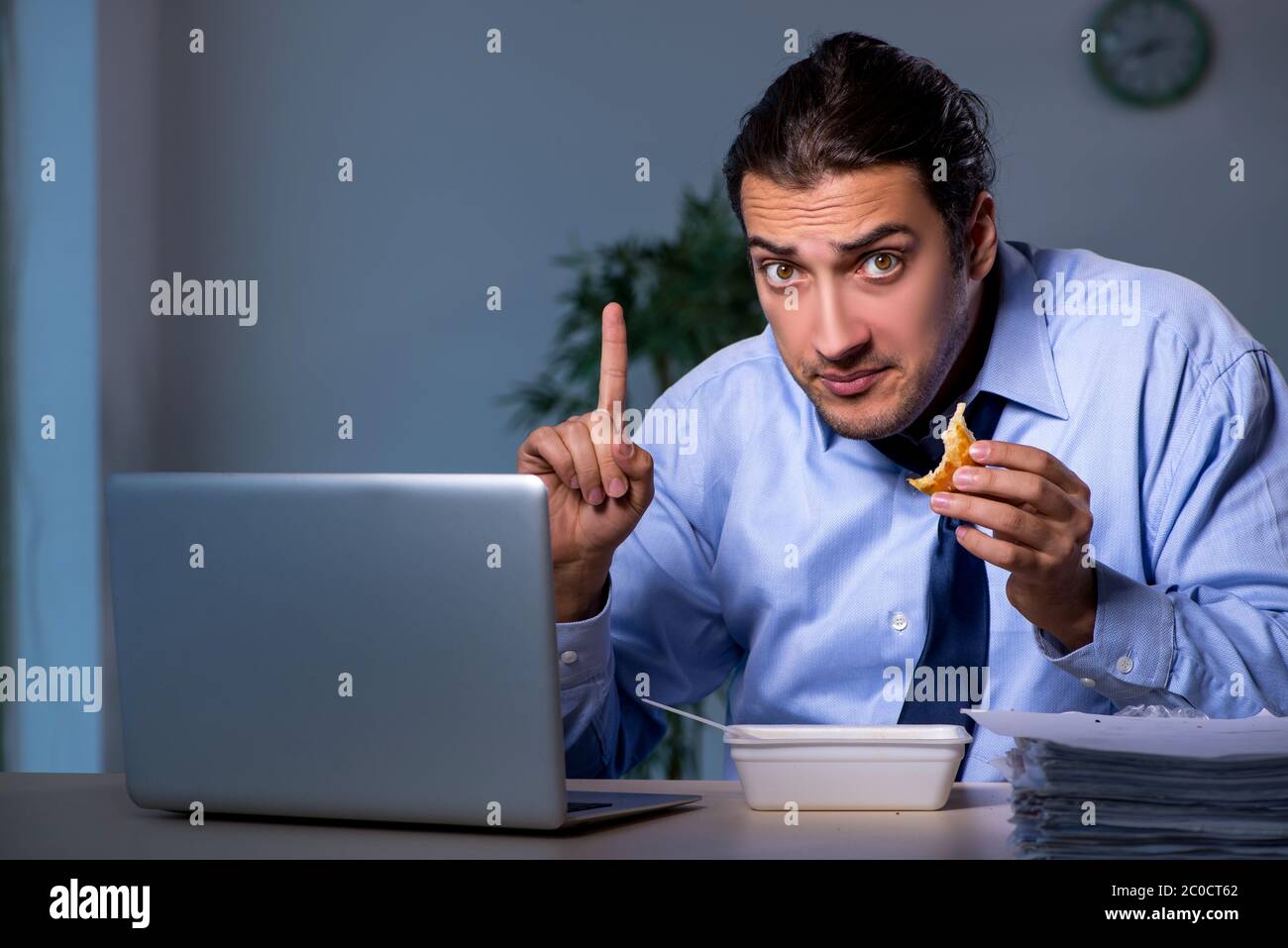 Hungry employee working late in office Stock Photo - Alamy