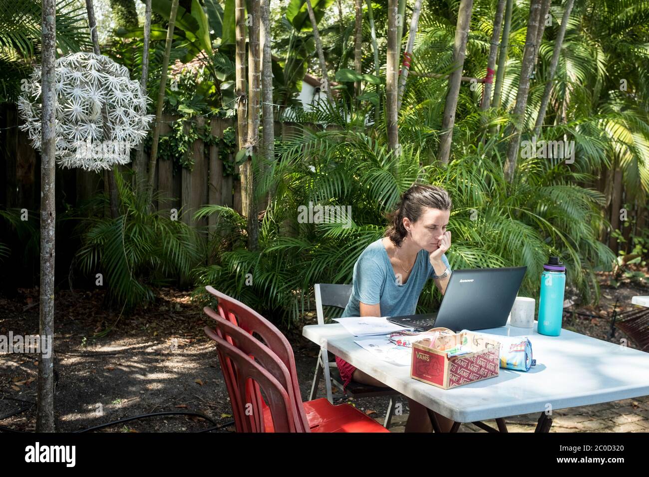 A casually dressed woman remote working and looking at her laptop ...