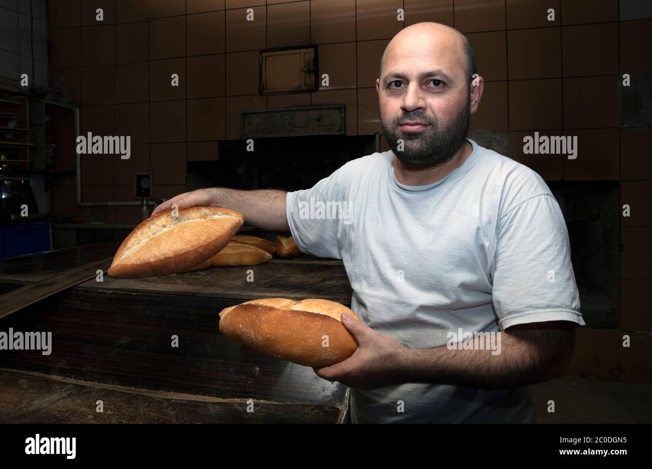 Young male worker working in bakery. She puts bread on shelf. Fresh ...