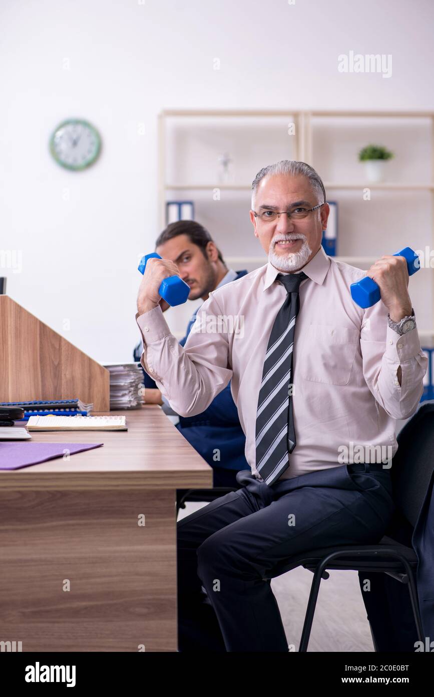 Two employees doing physical exercises at the workplace Stock Photo - Alamy