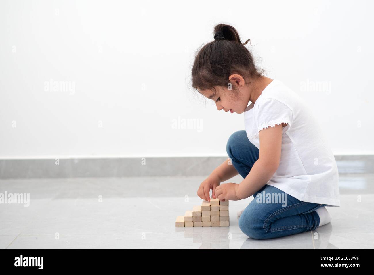 Cute child putting last block to the tower made of wooden blocks ...
