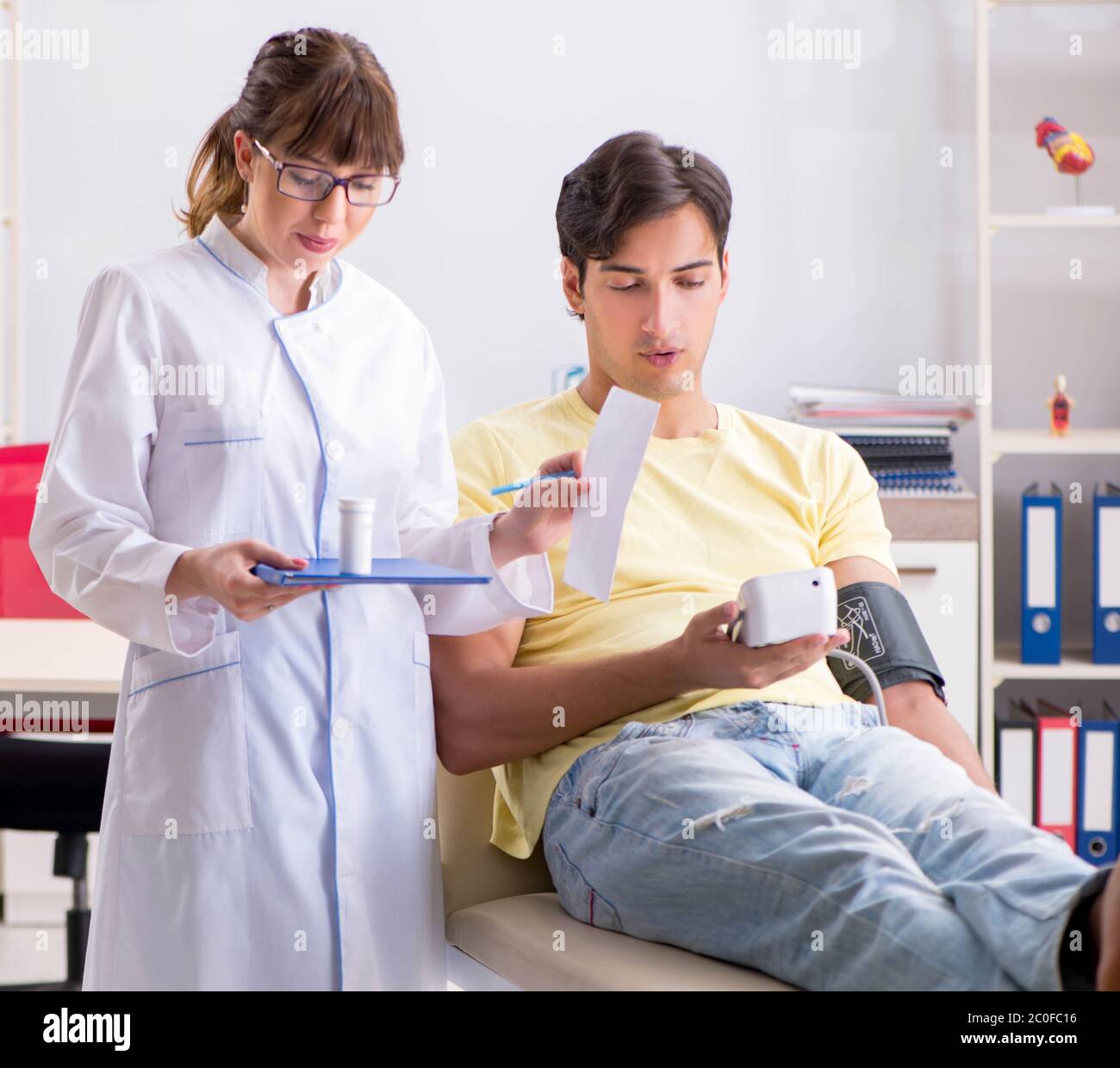 The young doctor checking patients blood pressure Stock Photo - Alamy