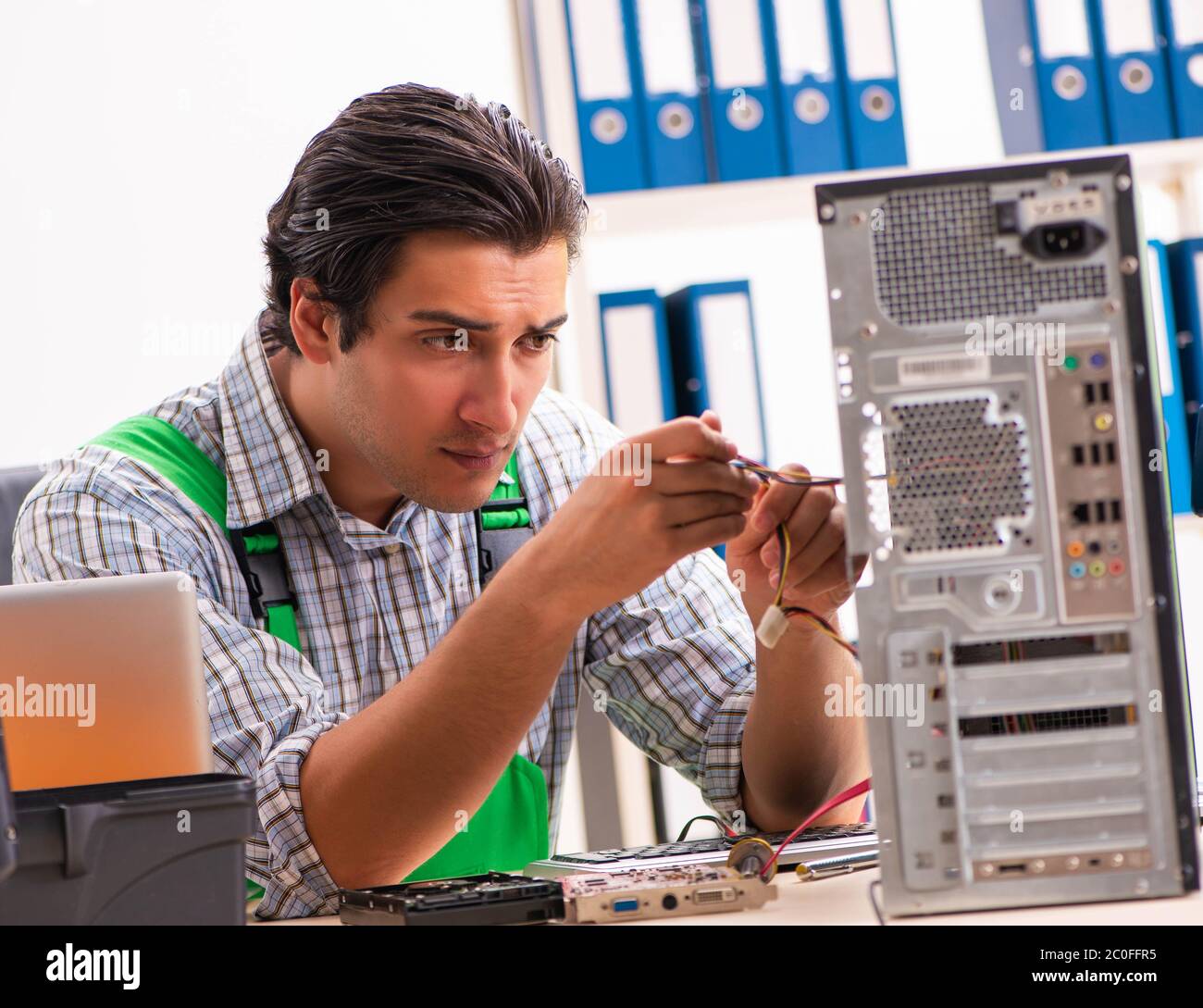 The young engineer repairing broken computer at the office Stock Photo ...