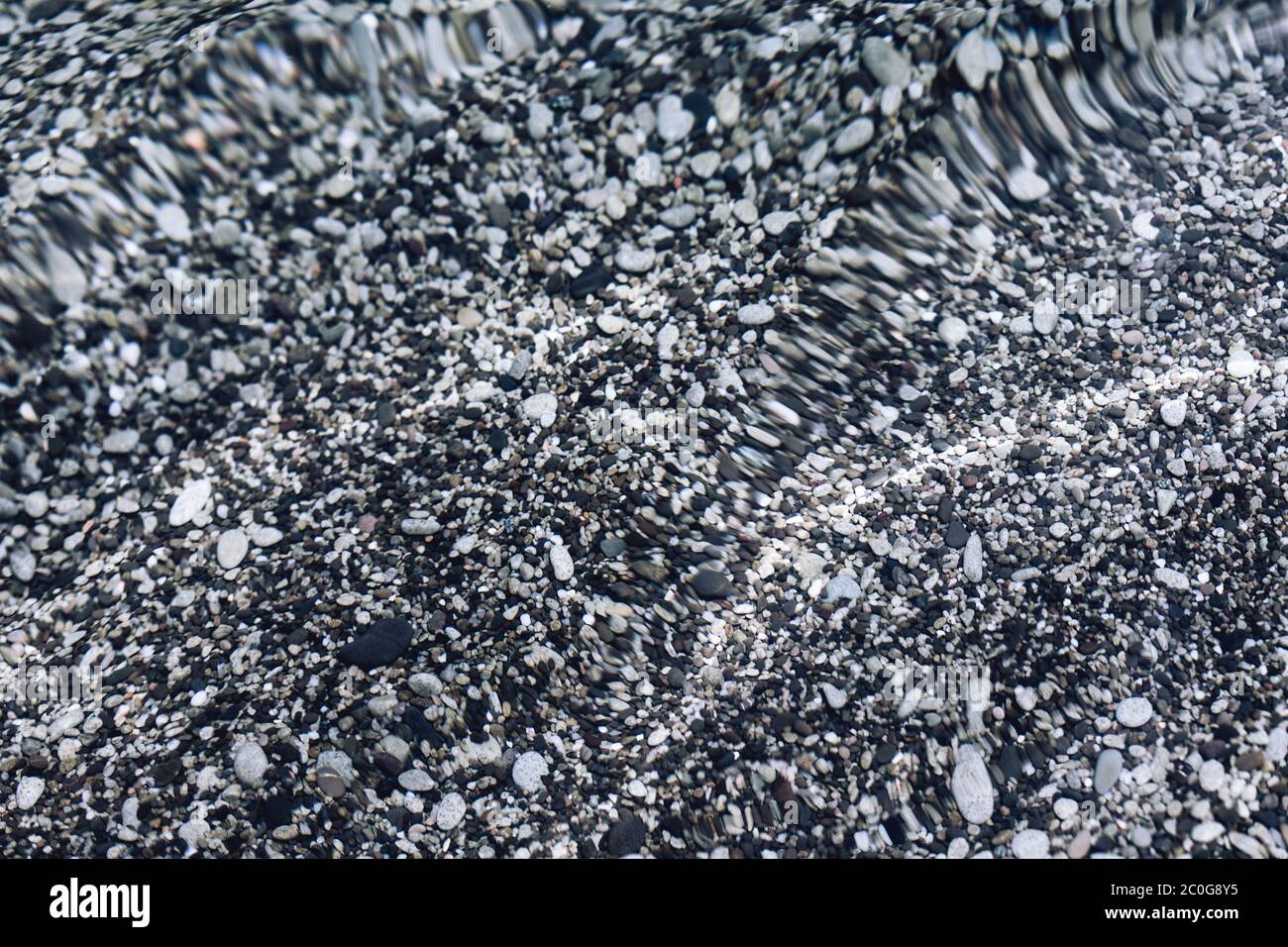 transparent clear calm water surface with small grey pebbles sea bottom ...