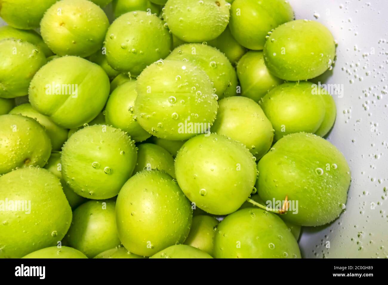 washed green plums in water Stock Photo - Alamy