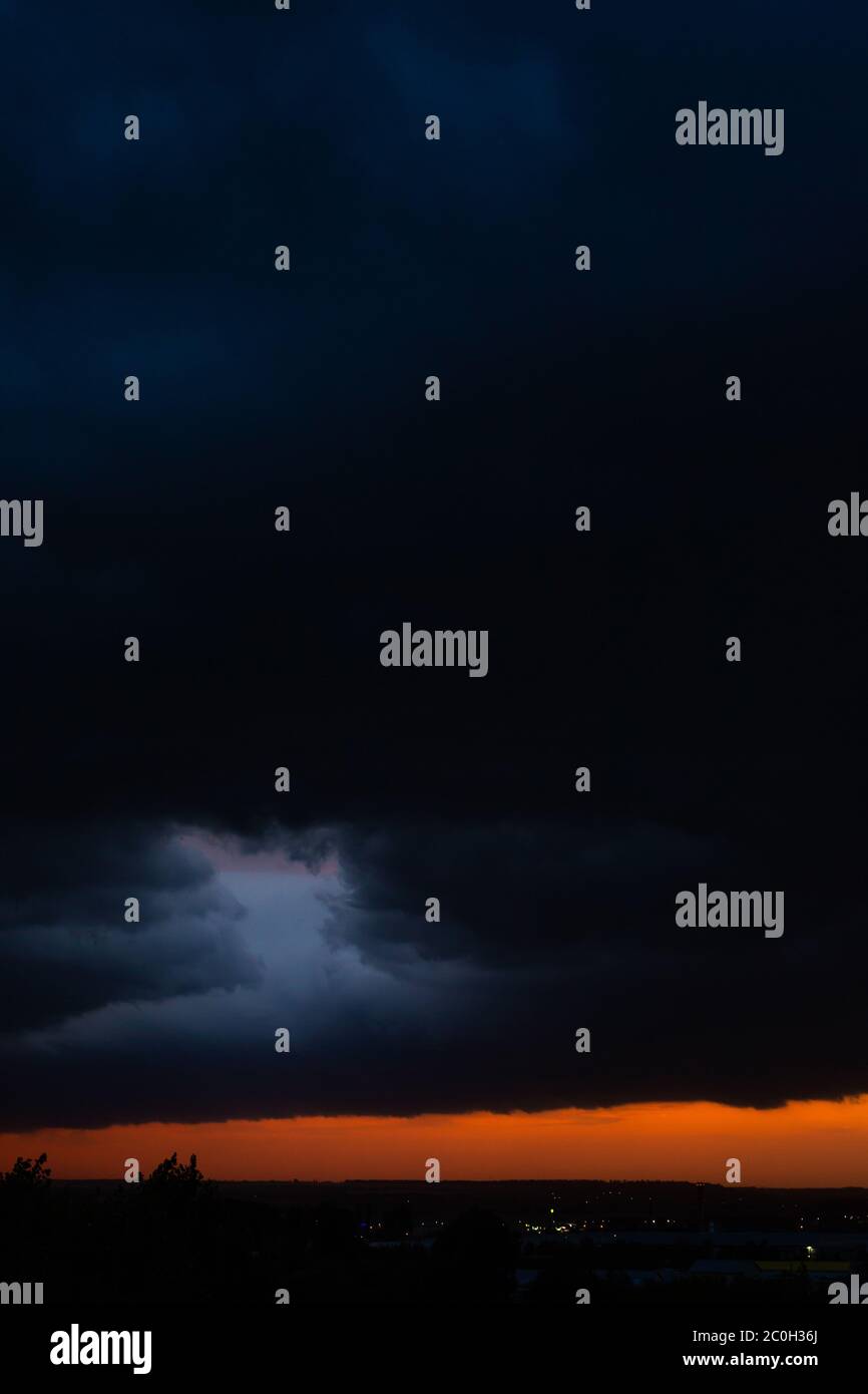 Black thunderclouds at sunset. Bright orange sunset and dark clouds ...