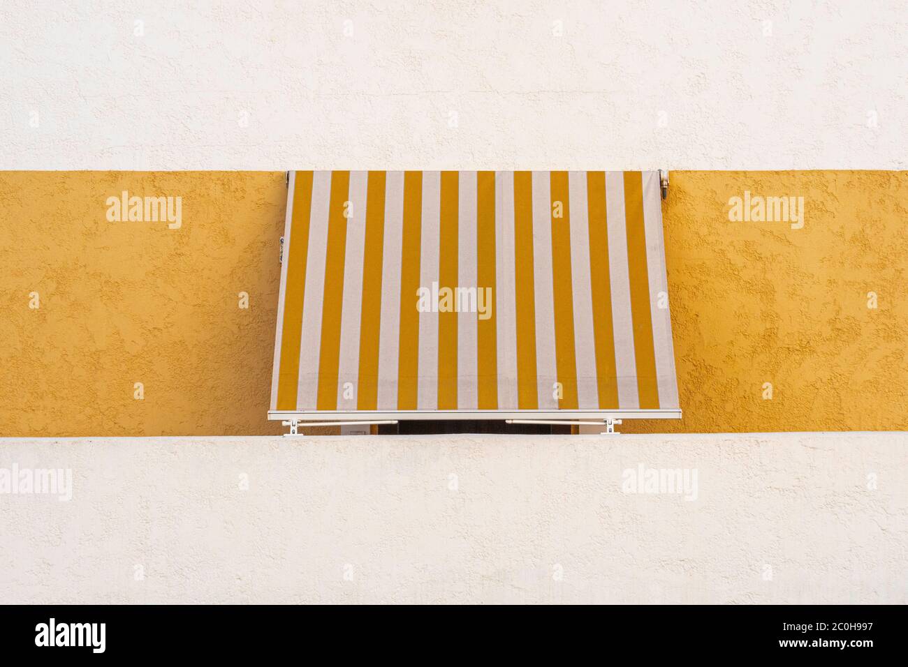 Window with striped shade sail sun protection in white and yellow wall ...