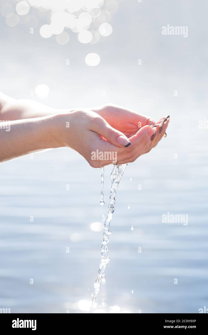 Water in the hands of a girl backlit by the sun. Life-giving moisture ...