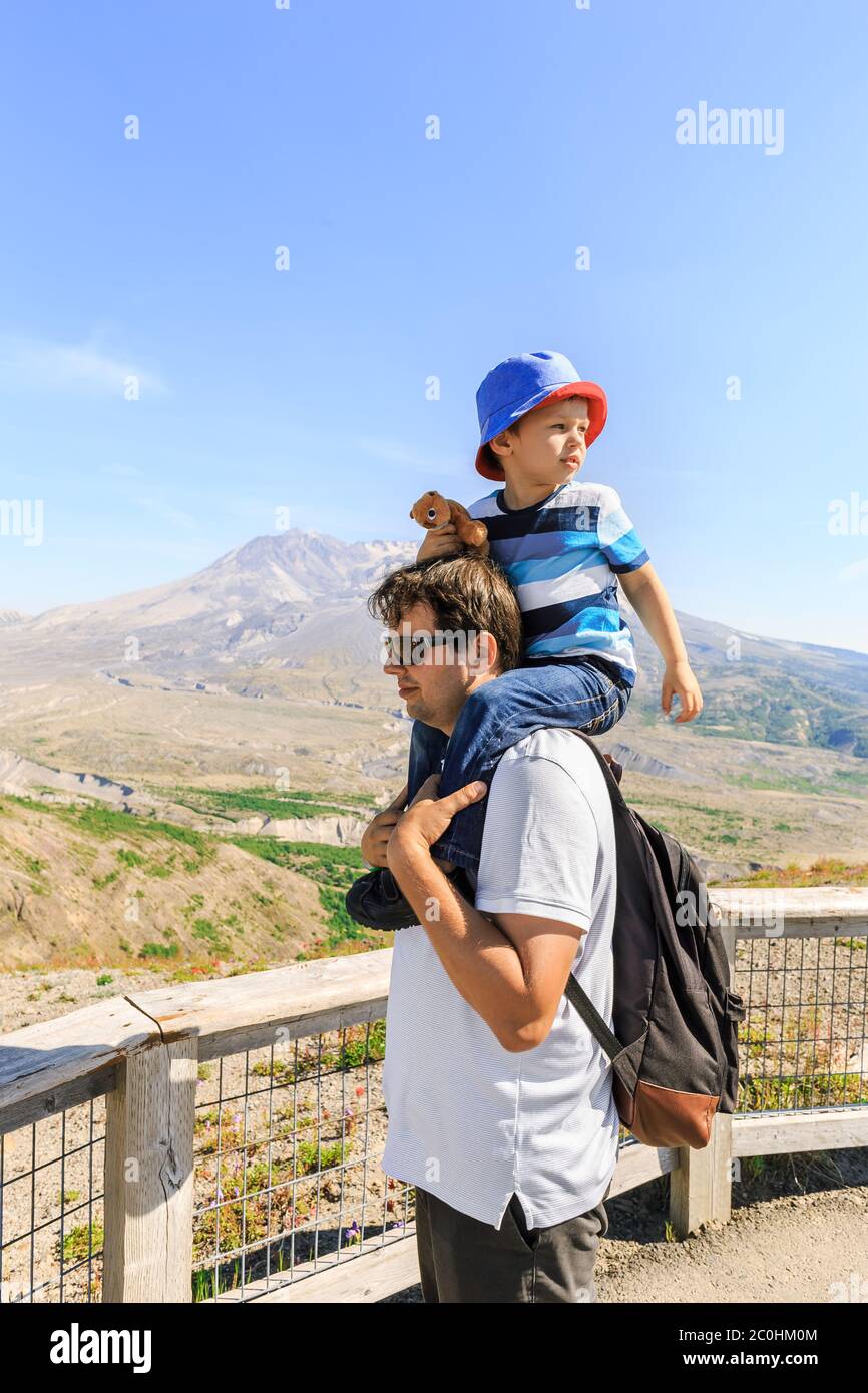 Happy father carrying on shoulders his little son who holds a funny ...