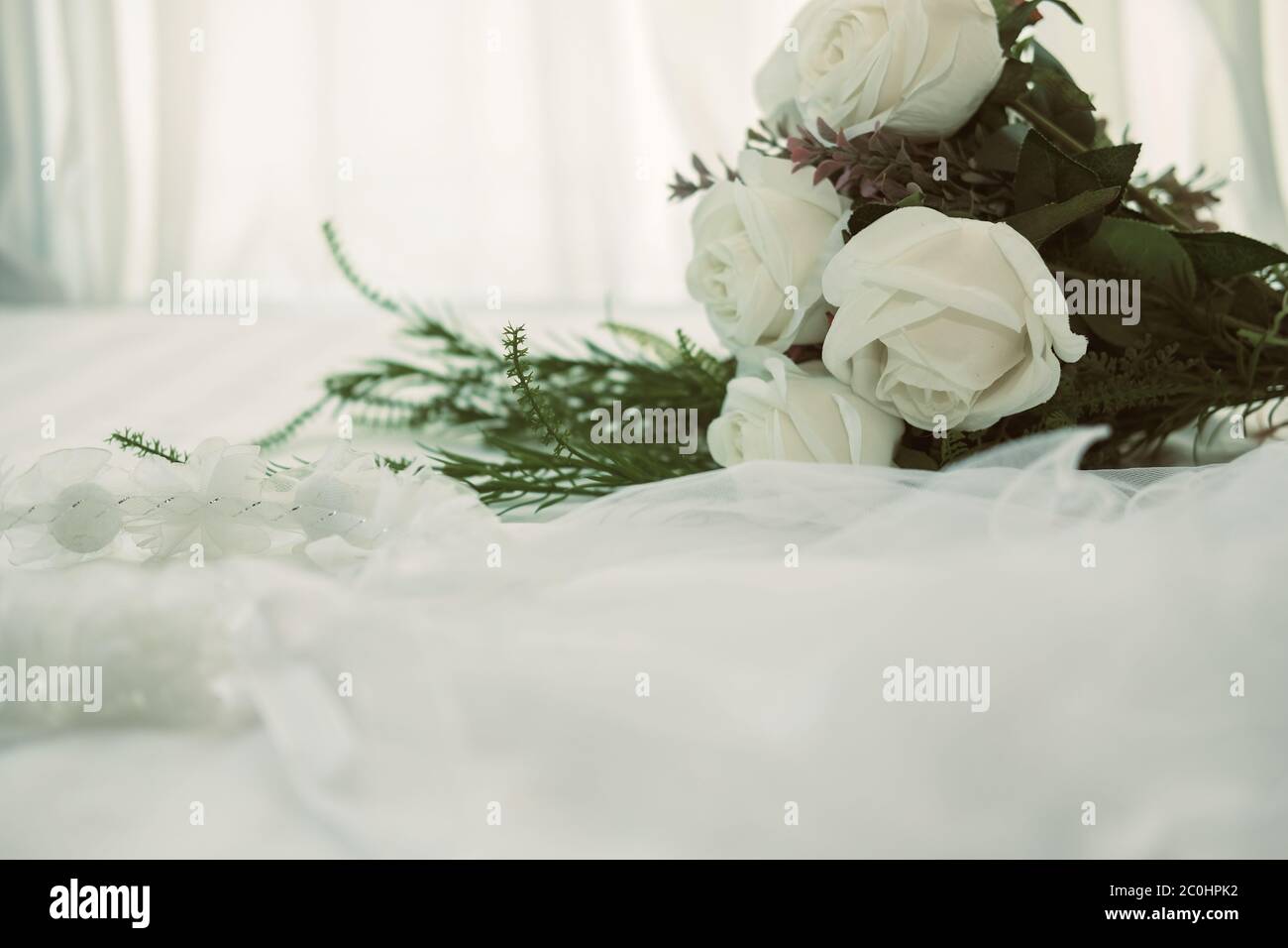 wedding white bridal veil & rose flower bouquet on bed beside see ...