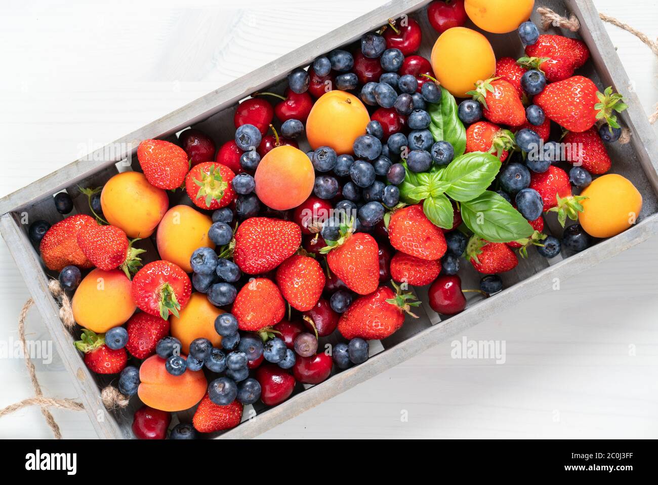 strawberries, blueberries, cherries and peaches in a wooden box Stock ...