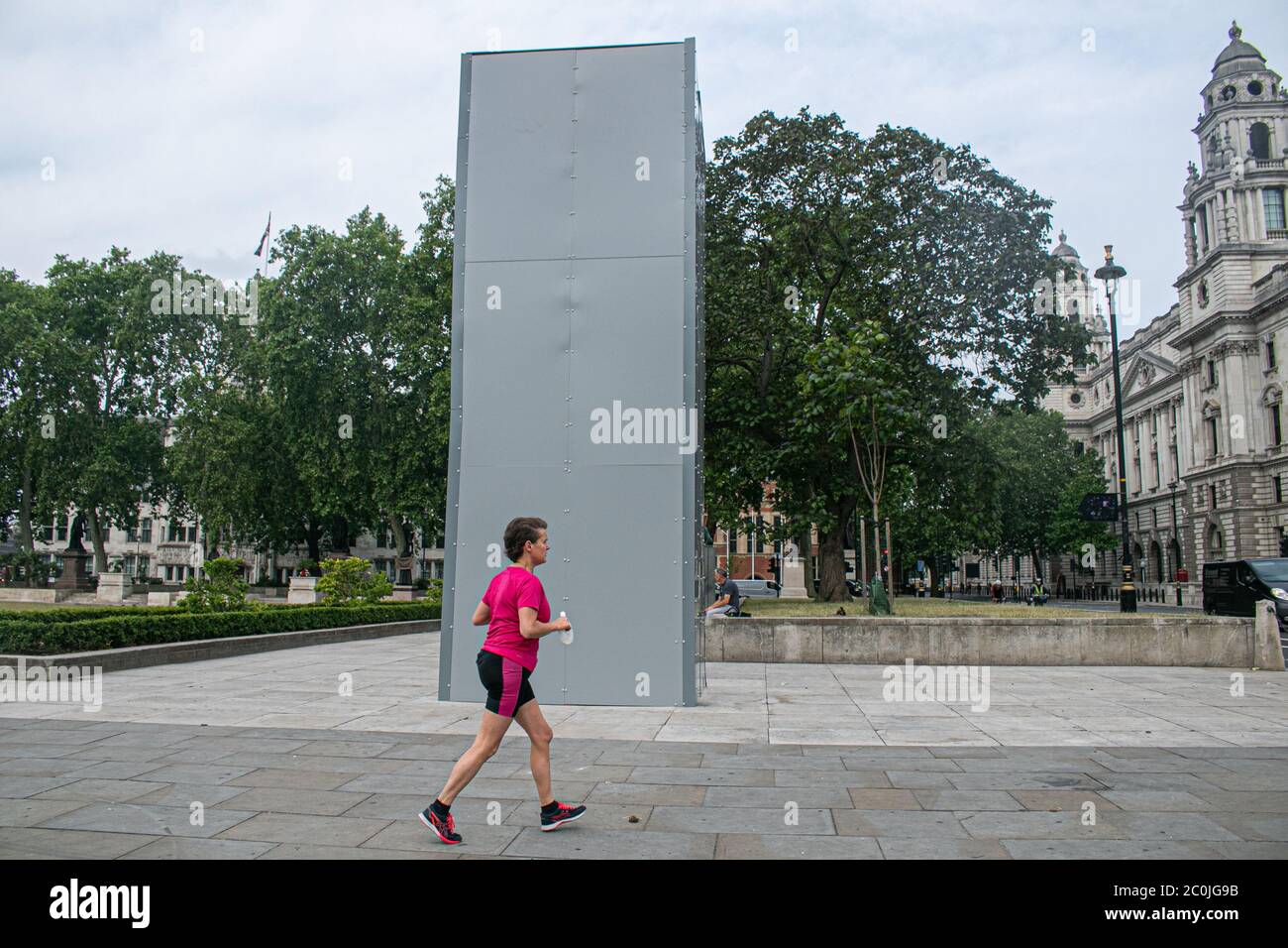 WESTMINSTER LONDON, UK. 12 June 2020. A jogger runs past the statue of ...