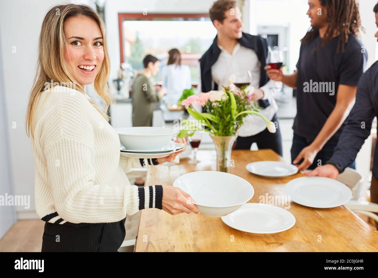 Woman laying table for lunch in shared kitchen with friends Stock Photo ...