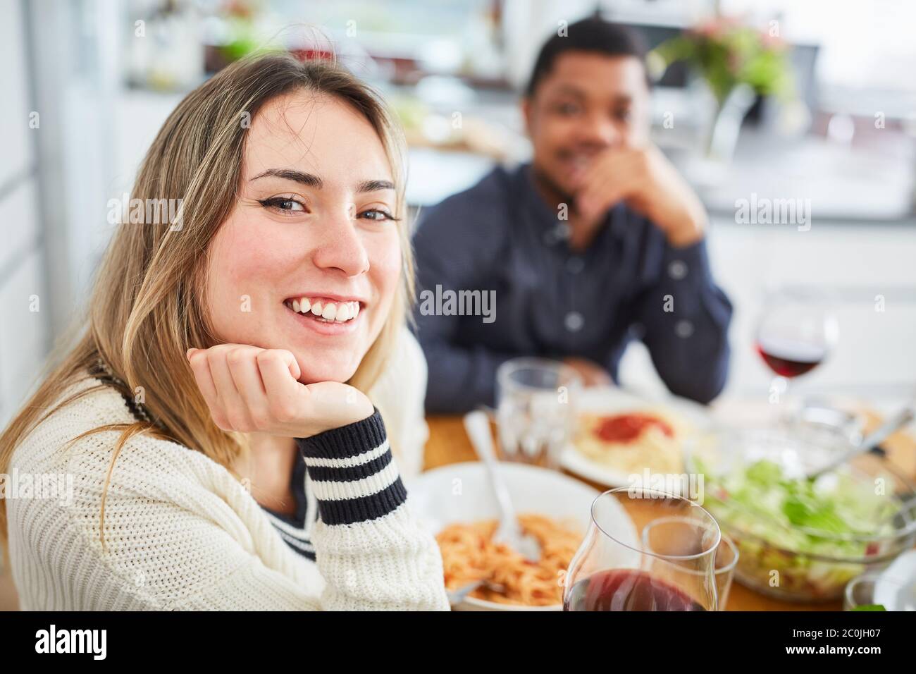 Happy friends eat pasta together at the table at lunch or dinner Stock ...