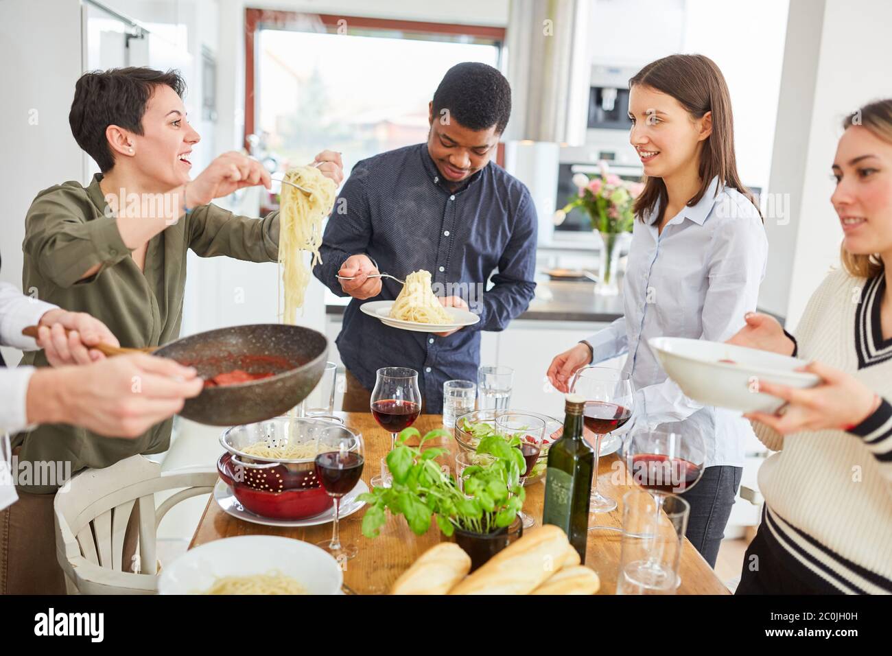 Group of friends served spaghetti with tomato sauce for eating in the ...