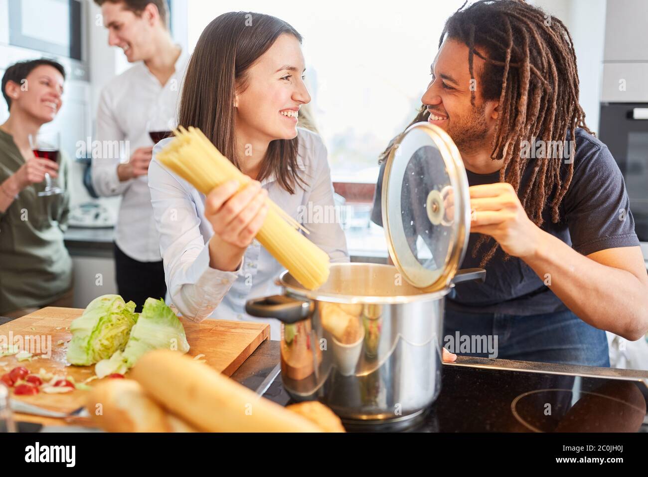 Happy friends cook spaghetti pasta together in kitchen for lunch Stock ...