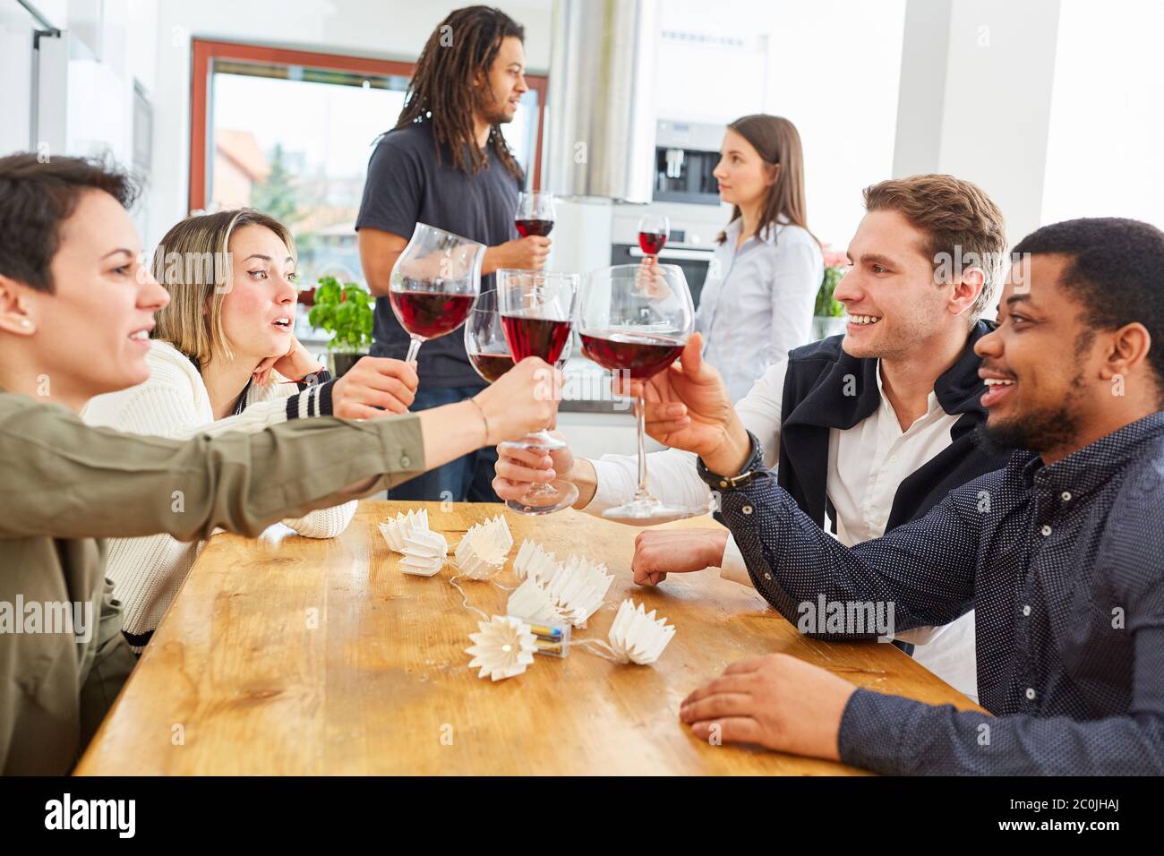 Group of students as friends drinking red wine together in the kitchen ...