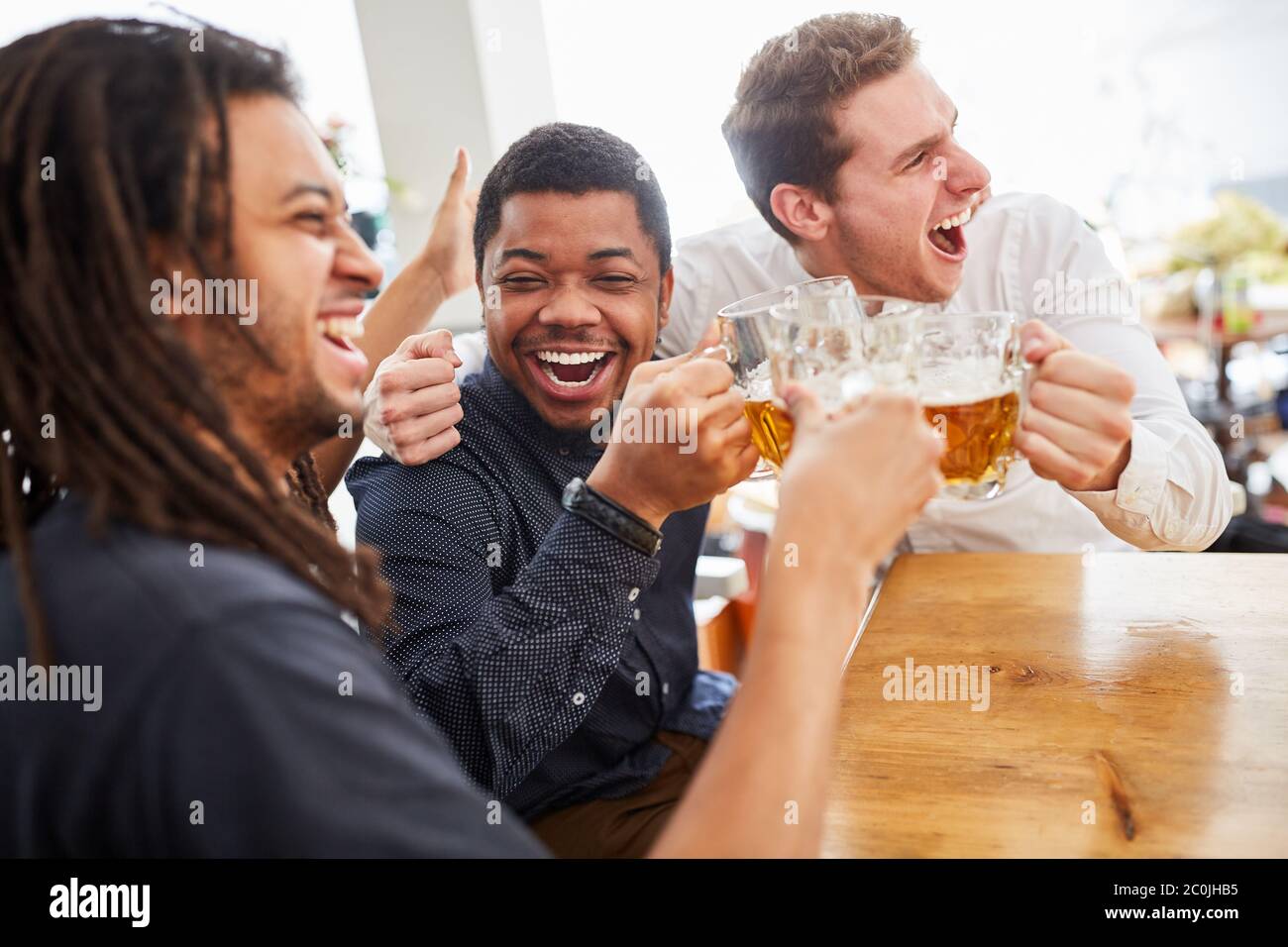 Group of men as friends cheers while drinking beer and clinking glasses ...