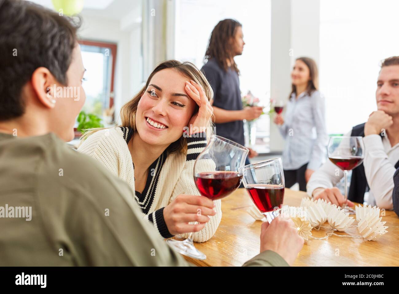 Friends talk to each other in shared kitchen over glass of red wine ...