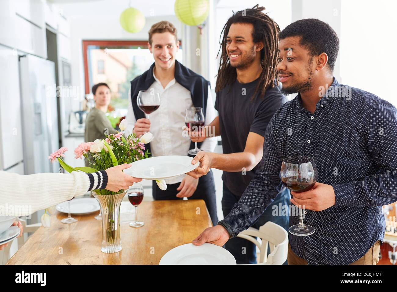 Happy friends at table setting together in student shared flat for ...