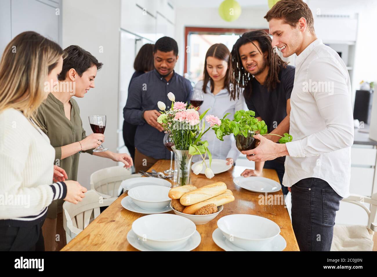 Group of friends in student flat share prepare dining table for meal ...