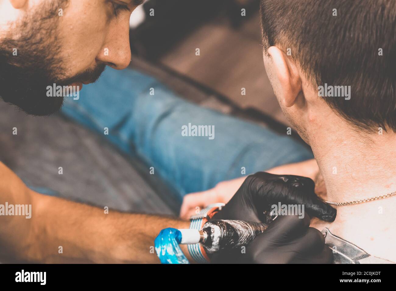 Tattoo salon. The tattoo master is tattooing a man on his shoulder ...