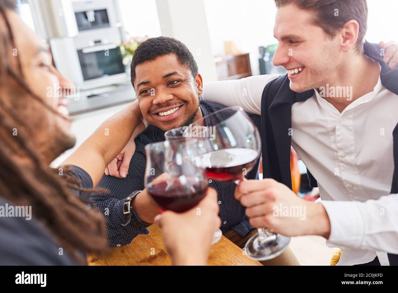 Men as friends hug while drinking wine and clink glasses with a glass ...