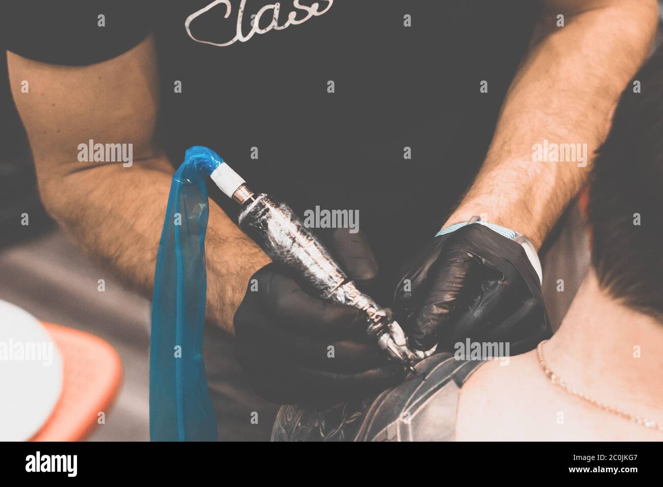 Tattoo salon. The tattoo master is tattooing a man on his shoulder ...