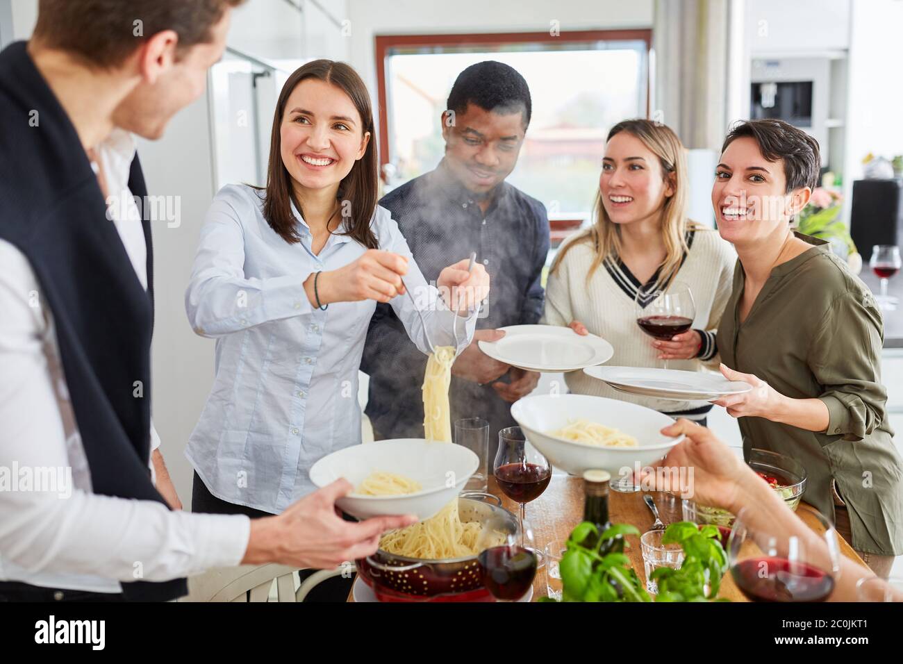 Group of friends serving spaghetti for a meal together in a shared ...