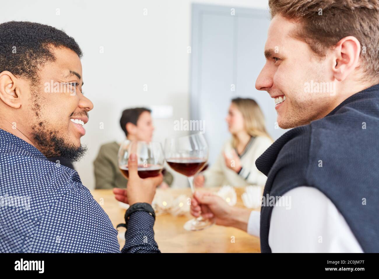Two men talk and clink glasses of wine at a birthday party Stock Photo ...