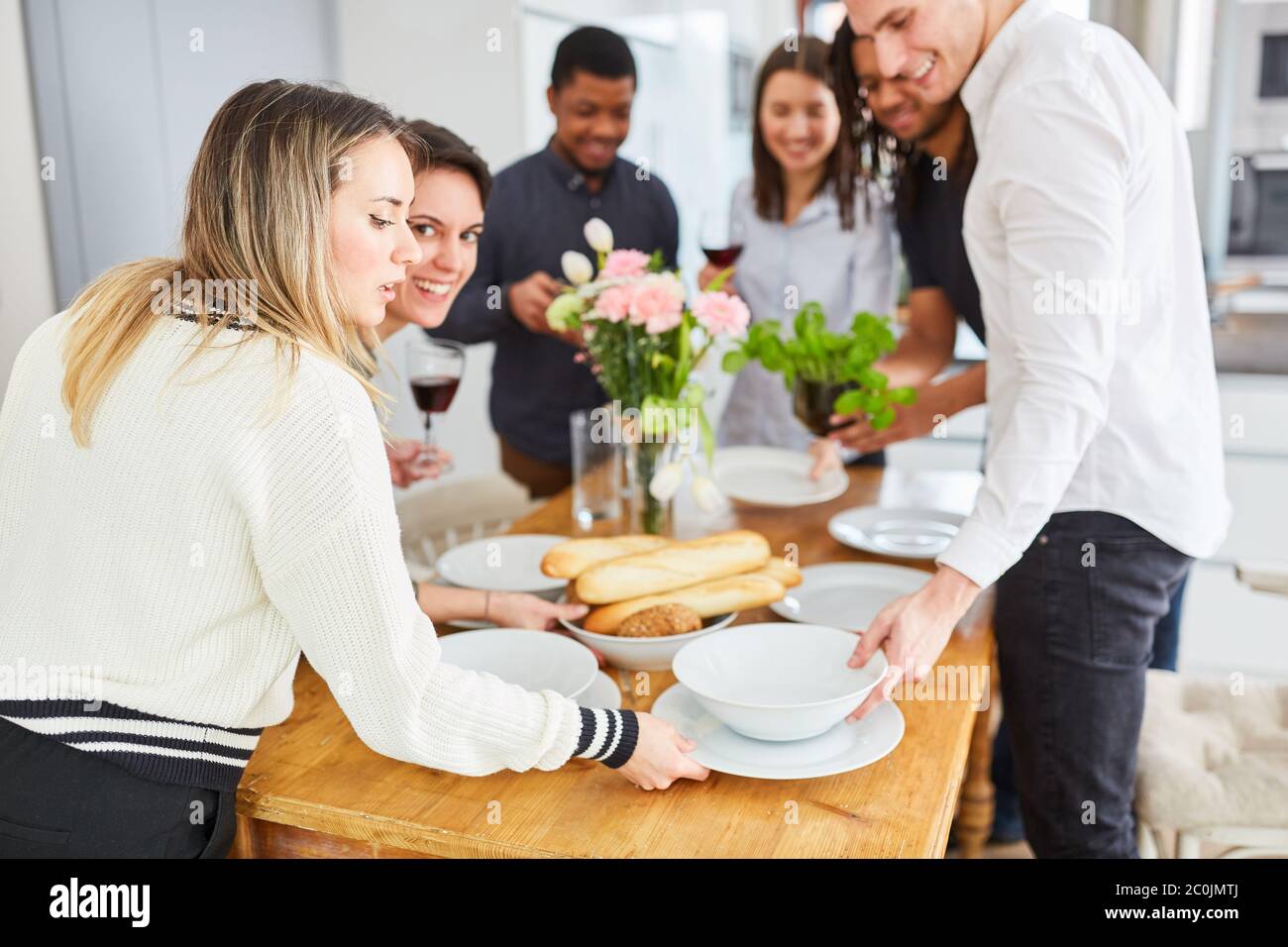 Group of friends in student shared flat set dining table for meal ...