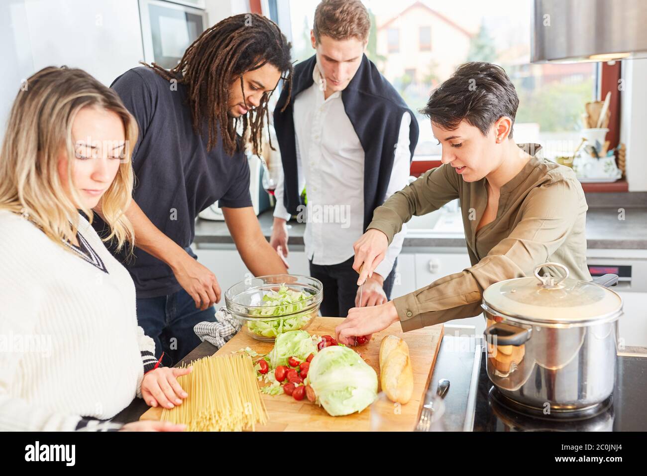Students as friends prepare salad and lunch together in a shared ...