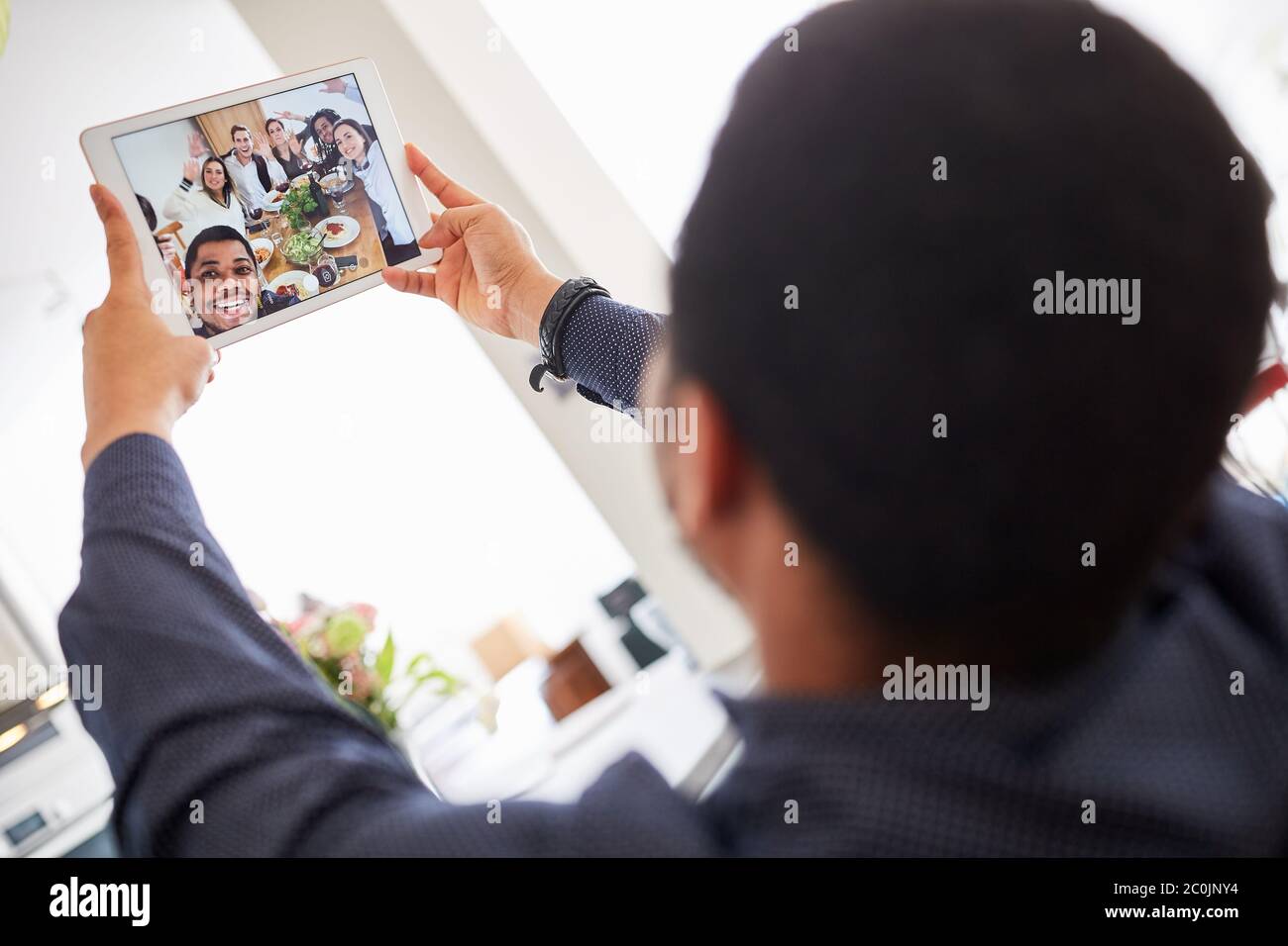African man making selfie with tablet computer from friends at meal at ...
