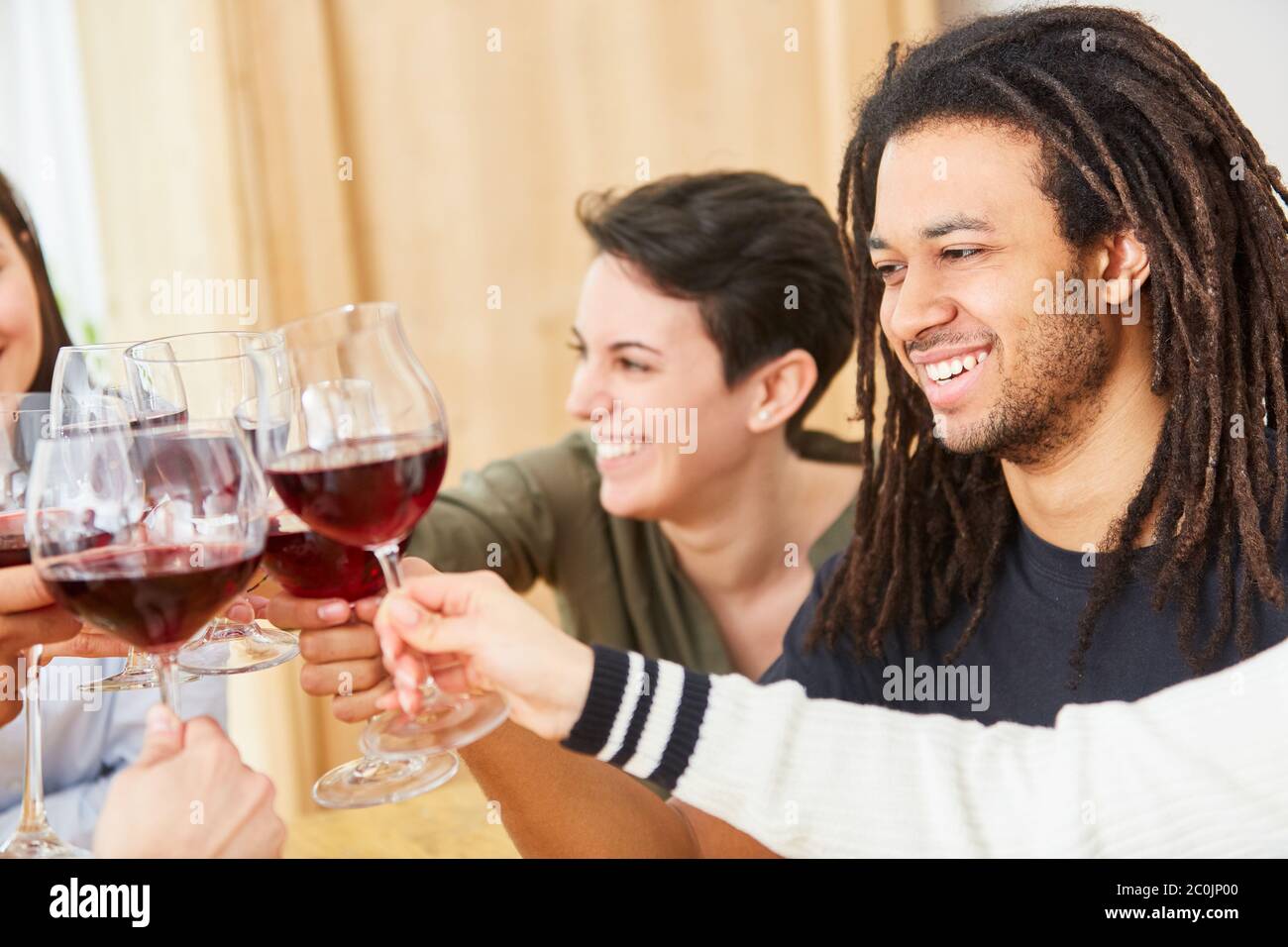 Happy group of friends toast together with glass of red wine at ...