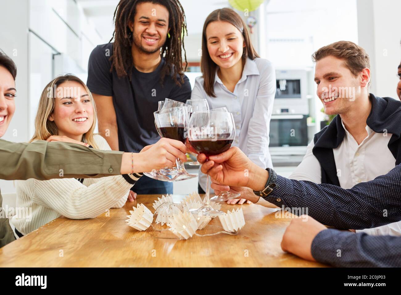 Happy group of friends together on a celebration in the kitchen toasts ...