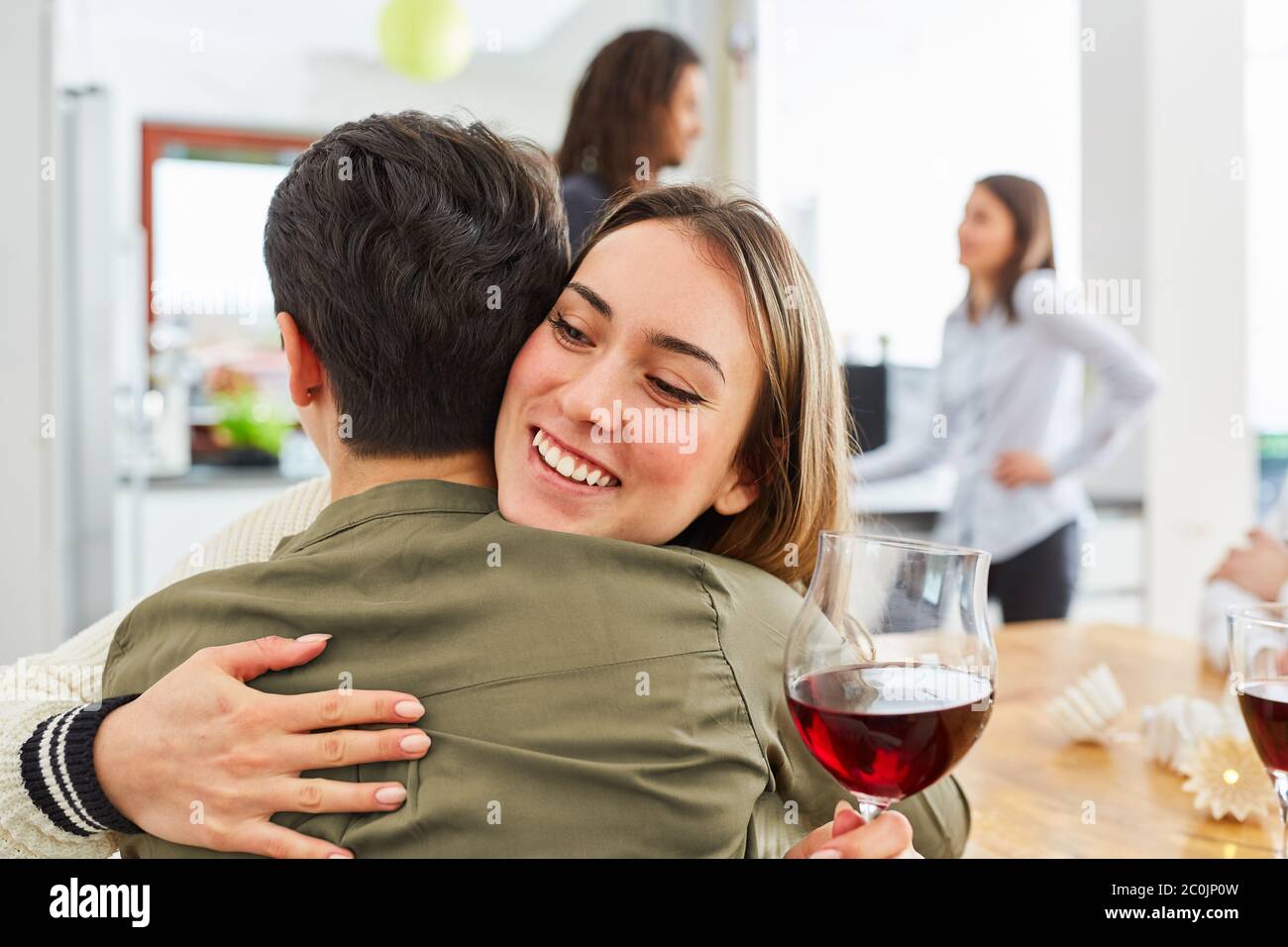 Two women as happy friends hug for joy at a celebration in a kitchen ...