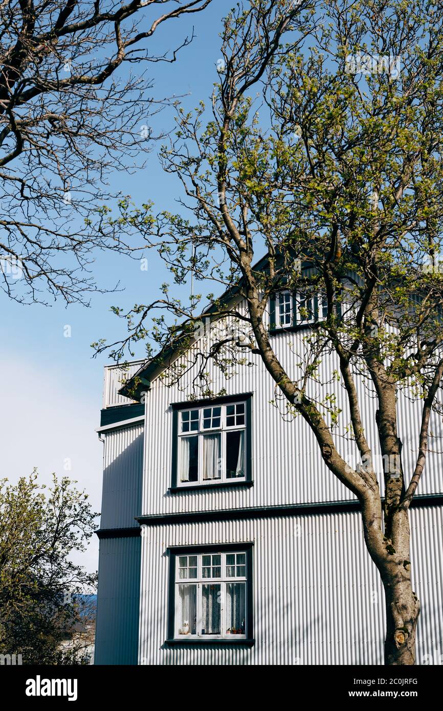 The corner of the facade of a gray metal house with wooden windows ...