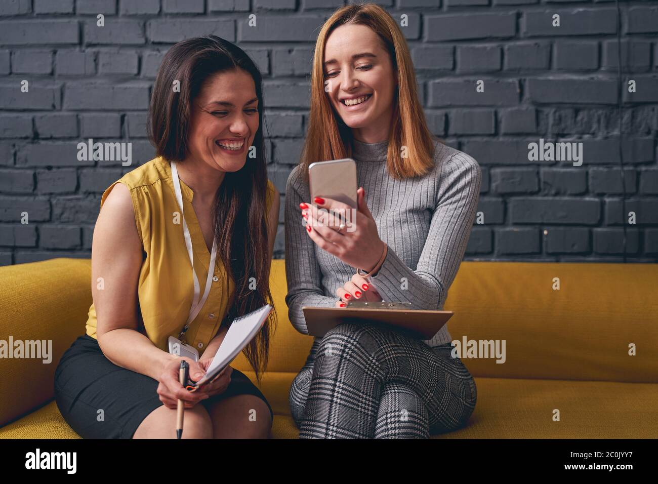 Two happy women laughing at funny picture Stock Photo - Alamy