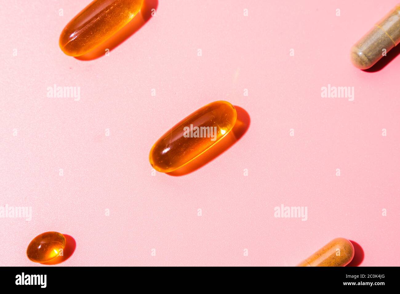 One omega 3 pill on pink background. Flat lay with harsh light and ...