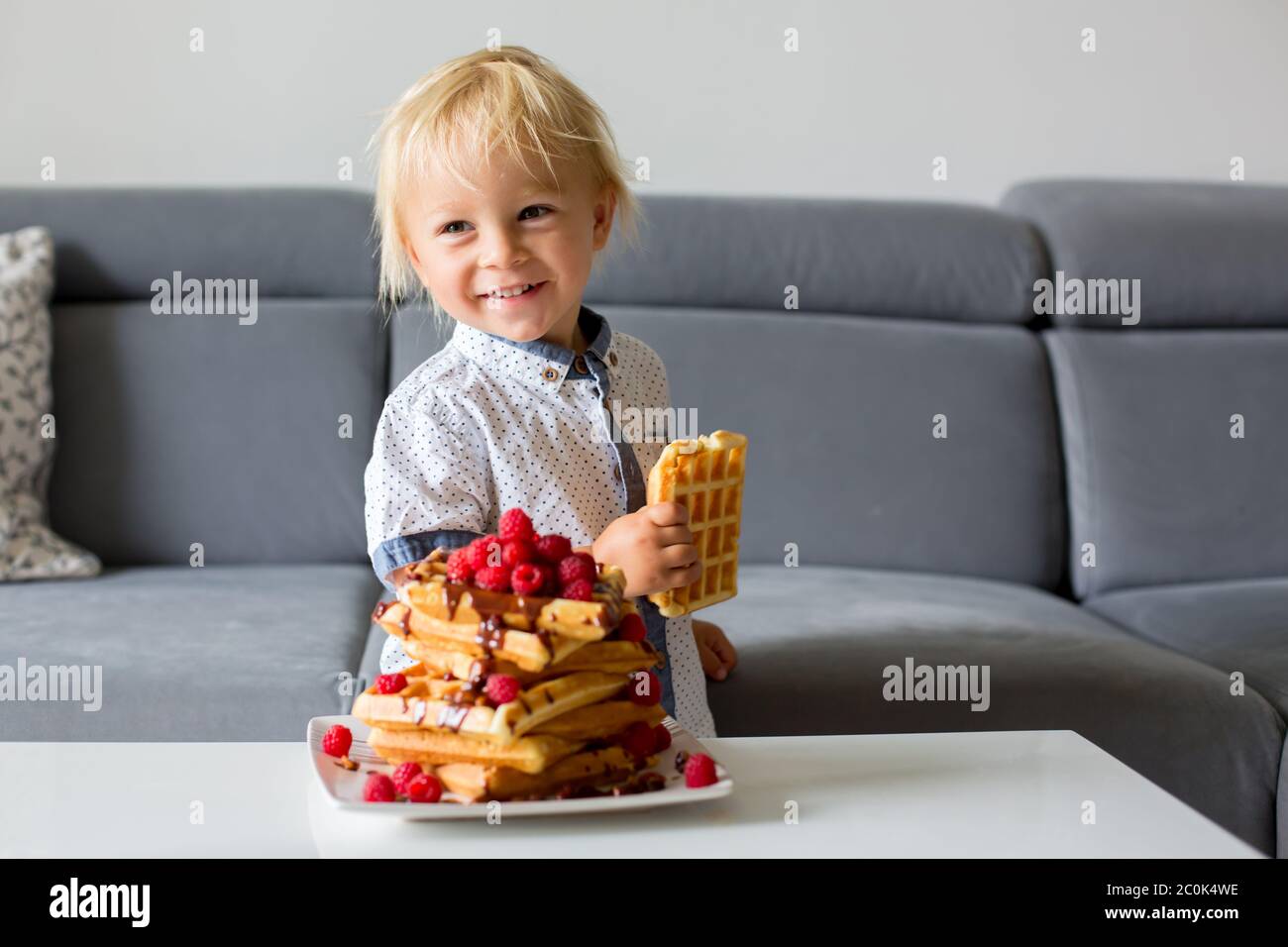 Sweet toddler birthday boy, eating belgian waffle with raspberries and ...