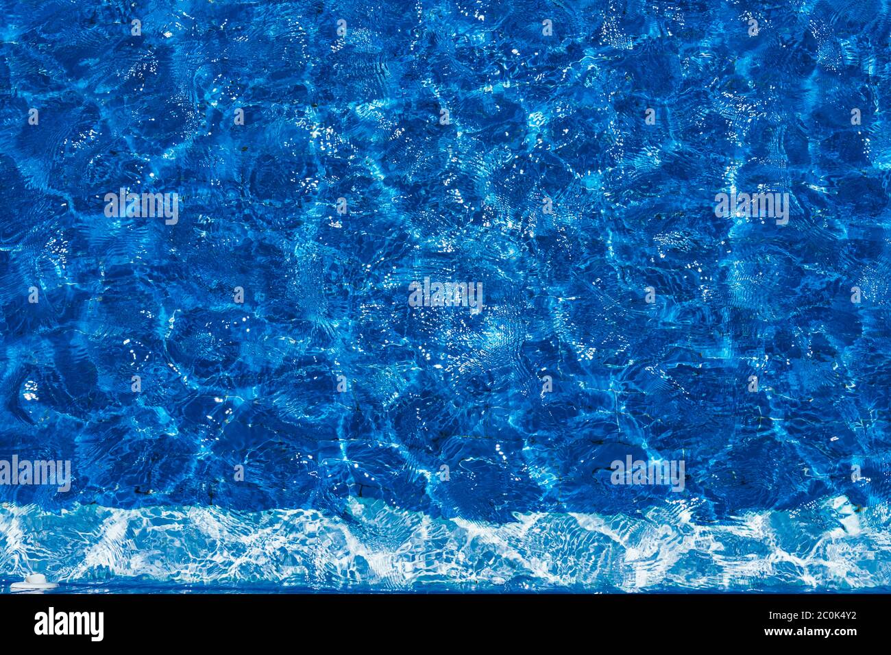 Swimming pool, blue clear water in the outdoor pool, with sun flare on ...