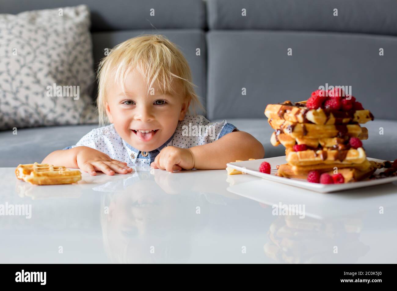 Sweet toddler birthday boy, eating belgian waffle with raspberries and ...