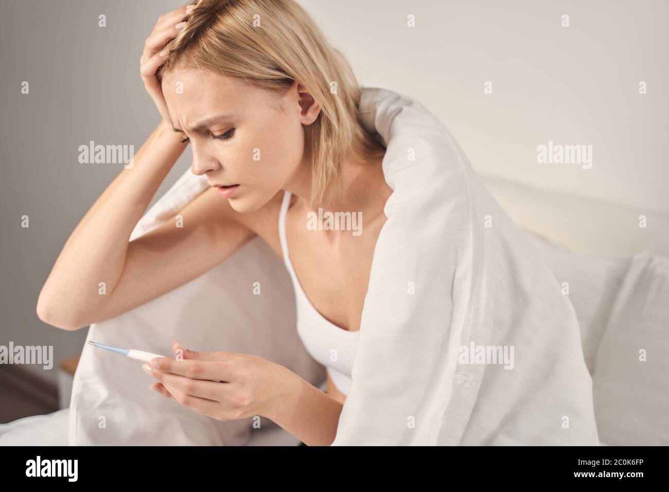 Frustrated lady staring at her digital thermometer Stock Photo - Alamy
